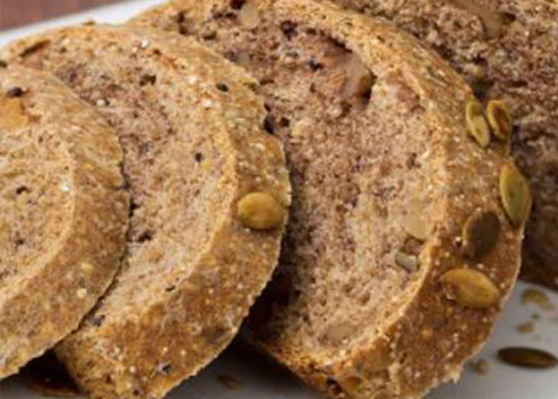 Image is of a loaf of bread with sunflower seeds that is sliced