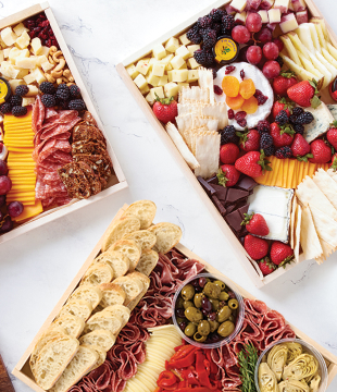 Premade cheeseboards with cheese, crackers, bread, fruit, salami and ...