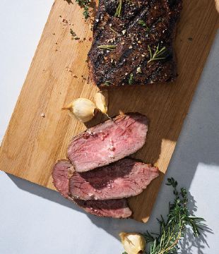 A juicy pre-marinated piece of meat ready to eat on top of a cutting board.