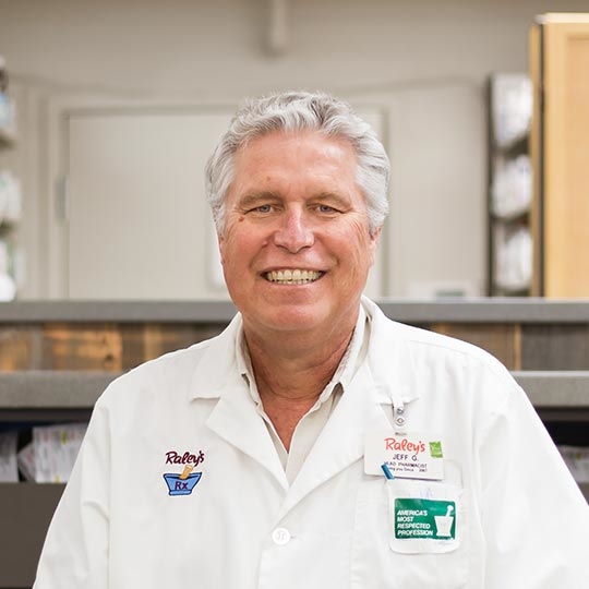 Image is of one of our Pharmacists smiling in a pharmacy